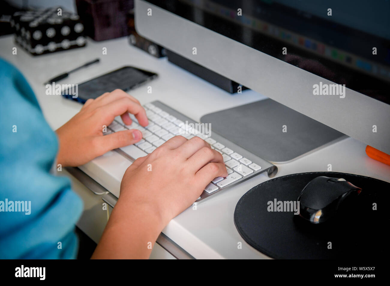 Hands of a teen working on the computer keyboard doing homework. Teenager working online ...