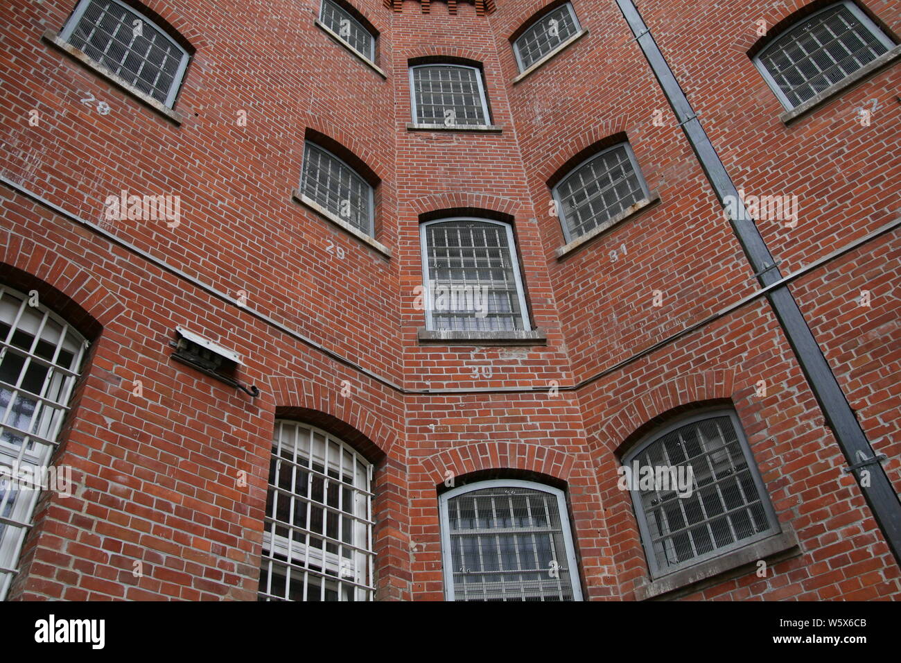 high prison wall with barred windows Stock Photo - Alamy