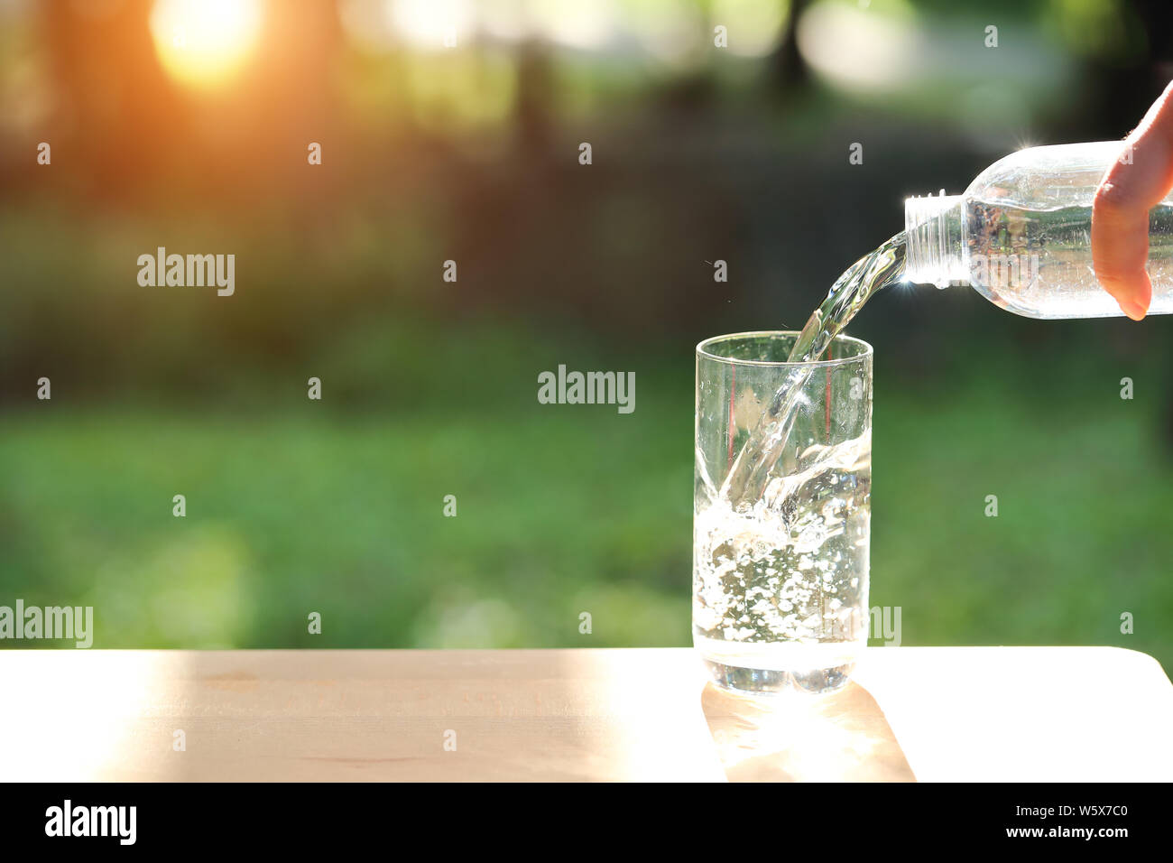 drink water pouring into empty glass with natural green background ...