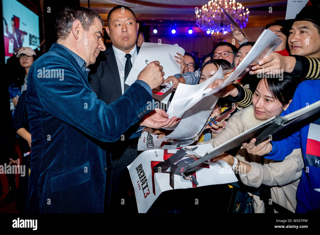 English actor Rowan Atkinson, left, signs autographs for fans during a ...