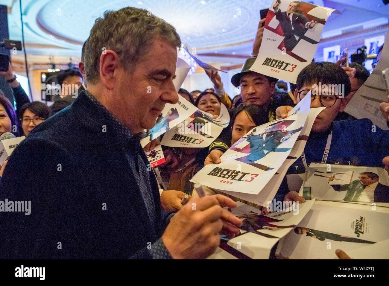 English actor Rowan Atkinson, left, signs autographs for fans during a ...
