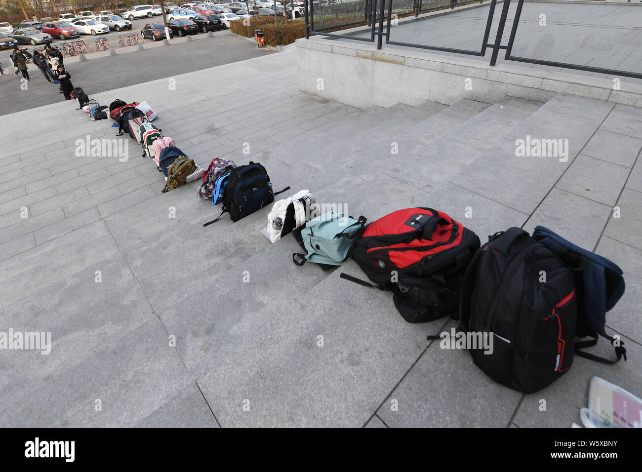 Students wait in line with their own bags for a seat in front of the ...