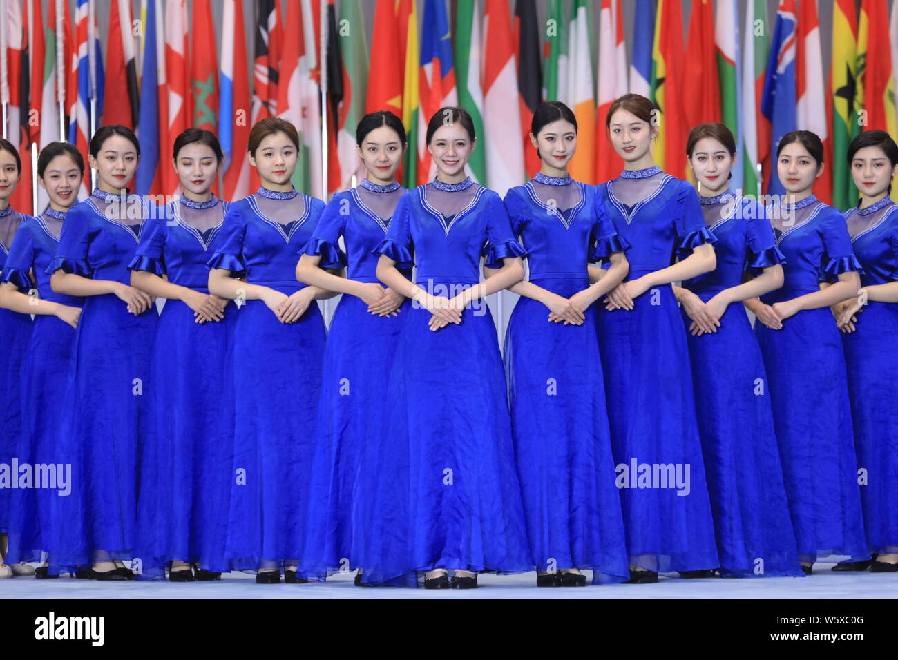 Chinese volunteers in blue uniforms pose for photos ahead of the ...