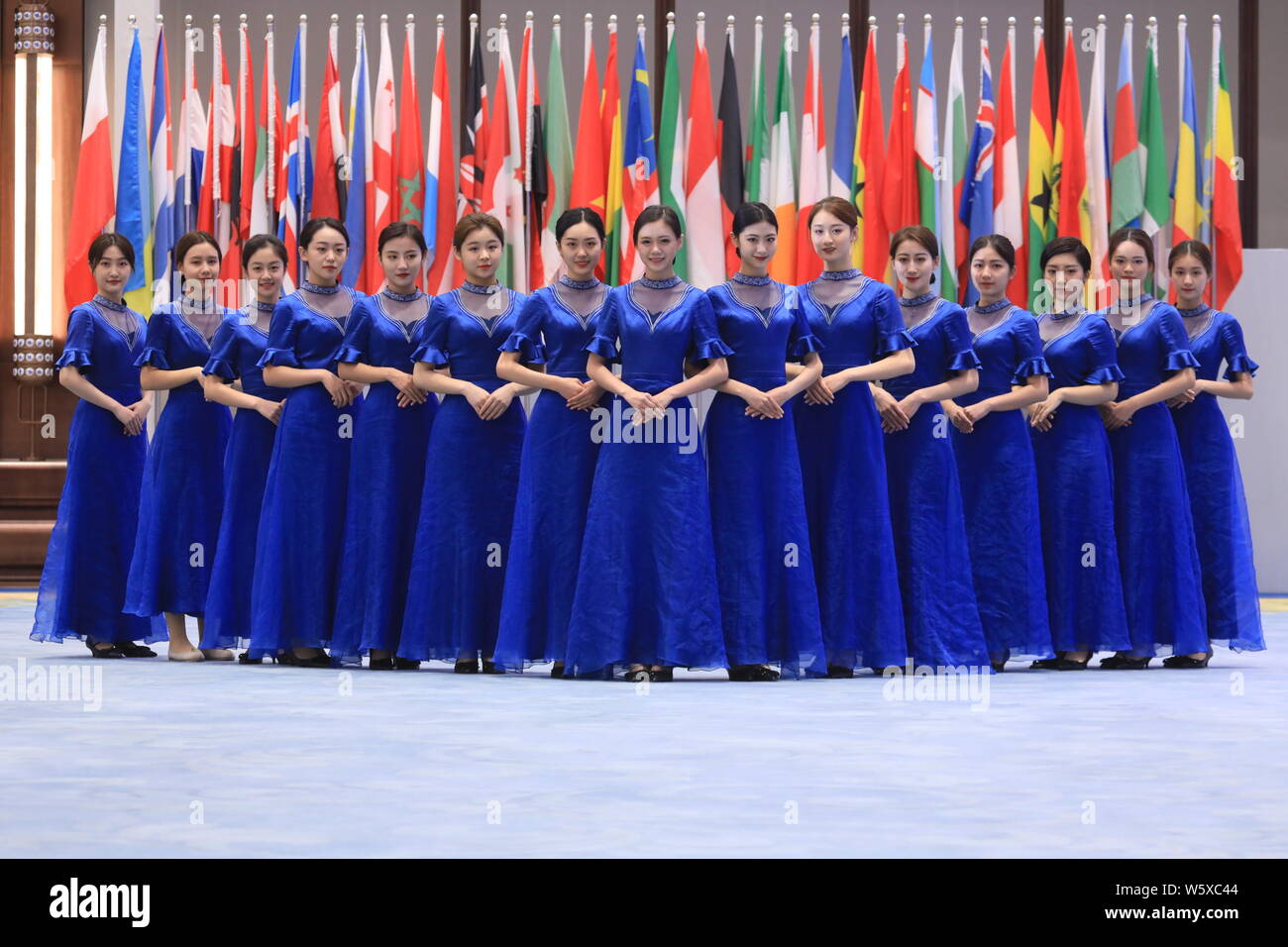 Chinese volunteers in blue uniforms pose for photos ahead of the ...