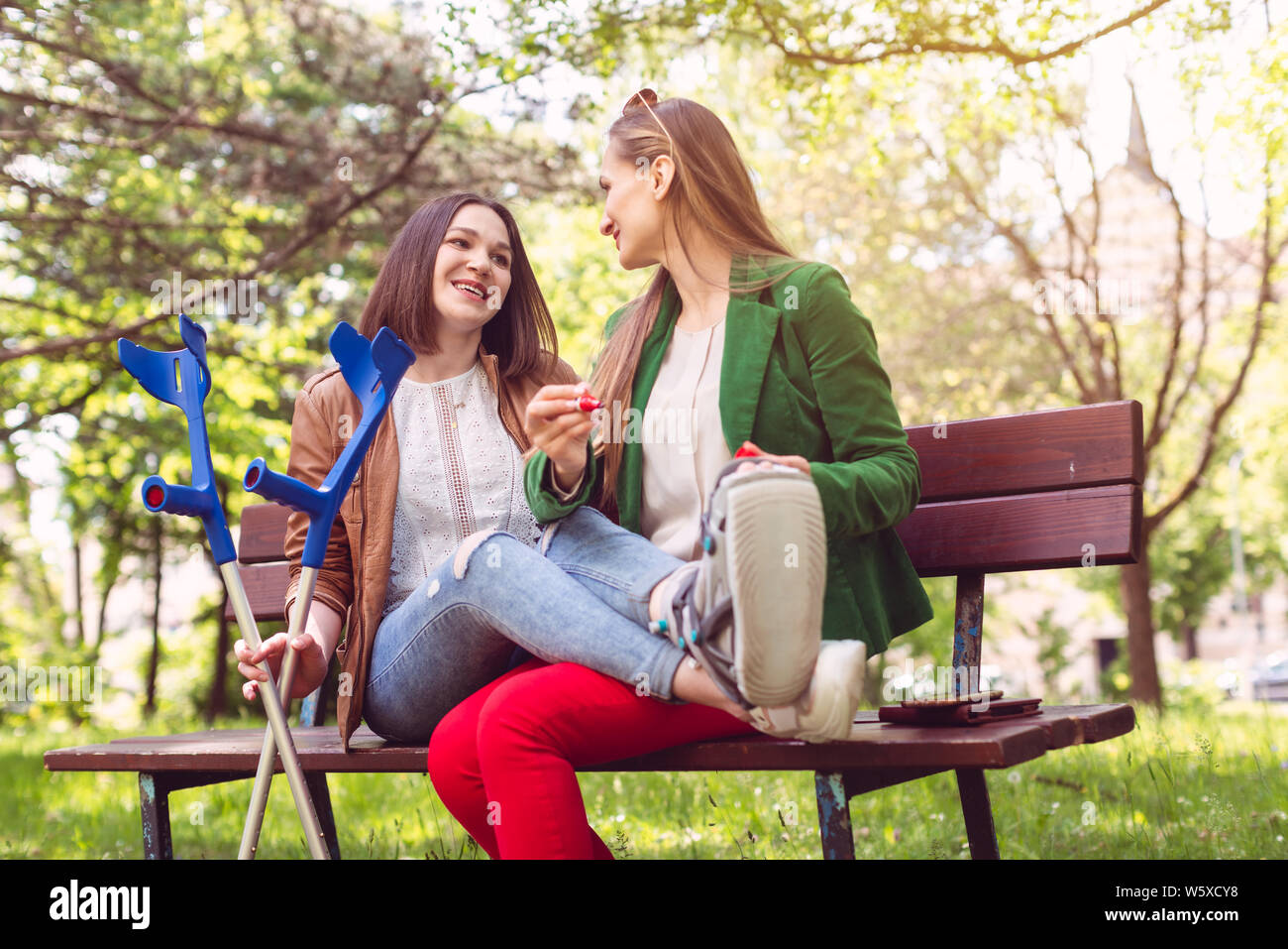 Healthy woman and friend with broken leg spending time together Stock ...