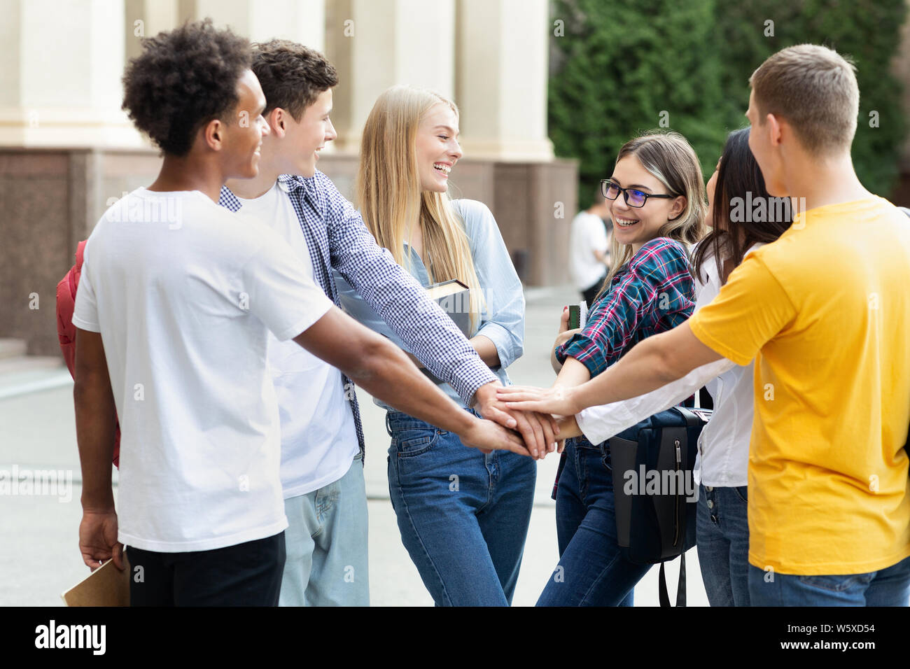 Togetherness, unity concept. Students putting their hands together ...