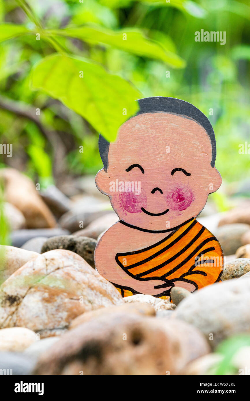 Little boy Buddhist, little Buddha, sitting on the sand on stones and ...