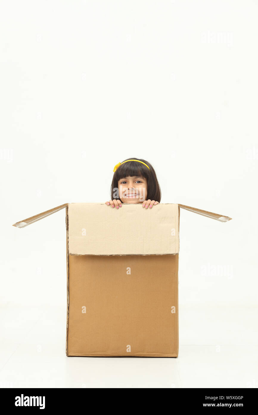 Girl peeking out of cardboard box Stock Photo - Alamy