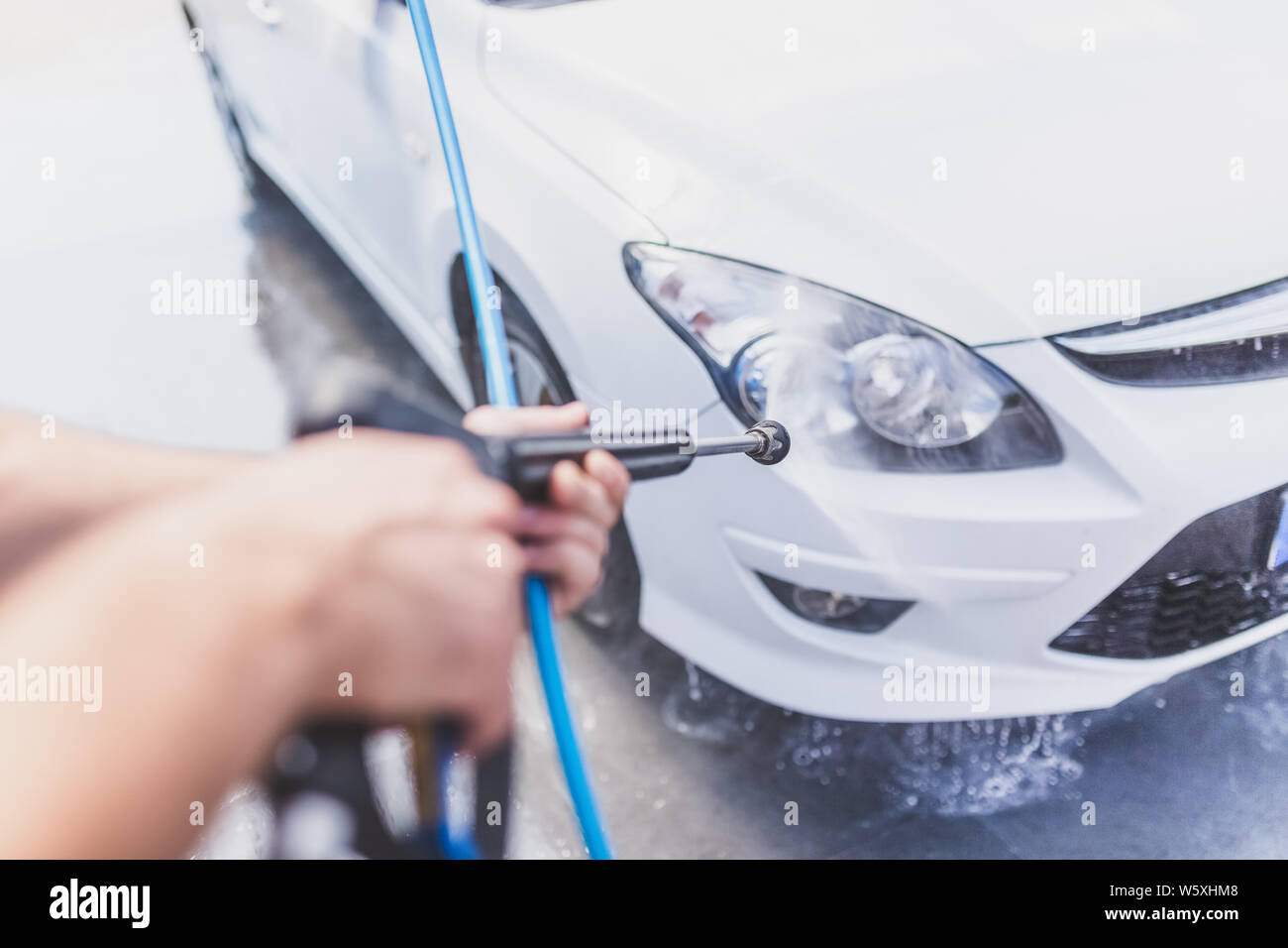 Close up of man washing his car with pressurized water in car wash ...