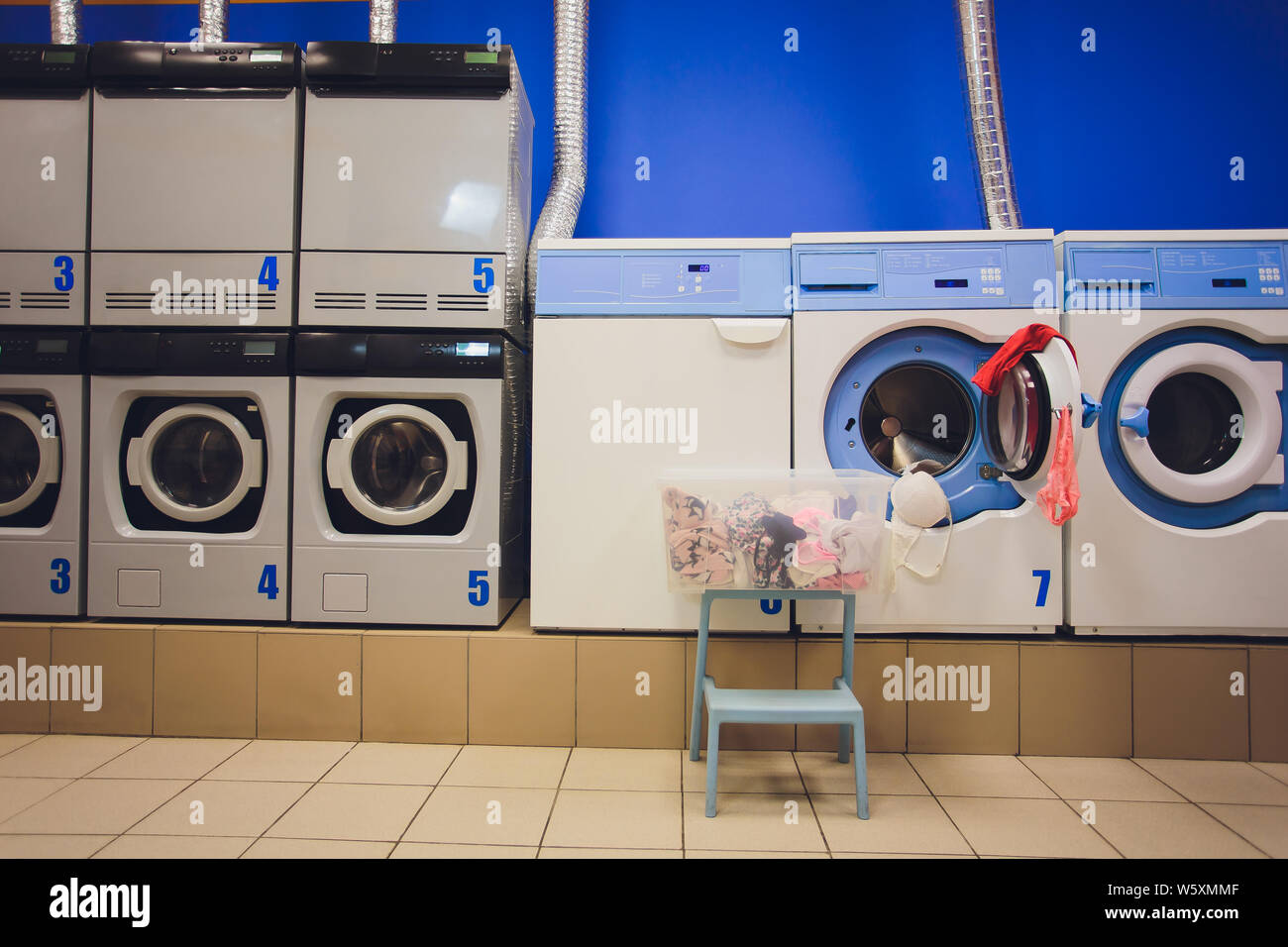 Professional washing machines with baskets full of clothes at the self ...