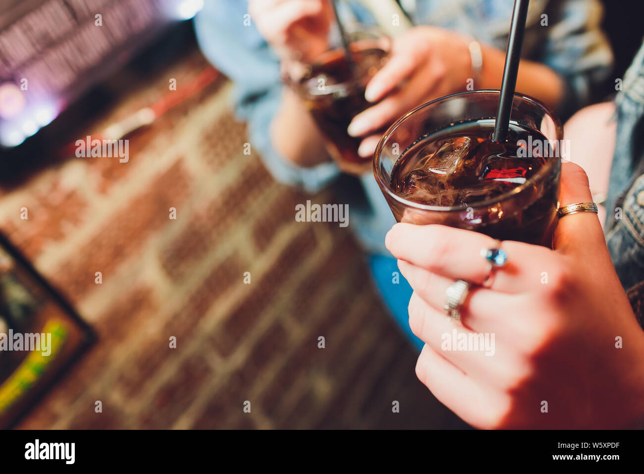 Cocktail glass in woman's hand with bar on back Stock Photo - Alamy