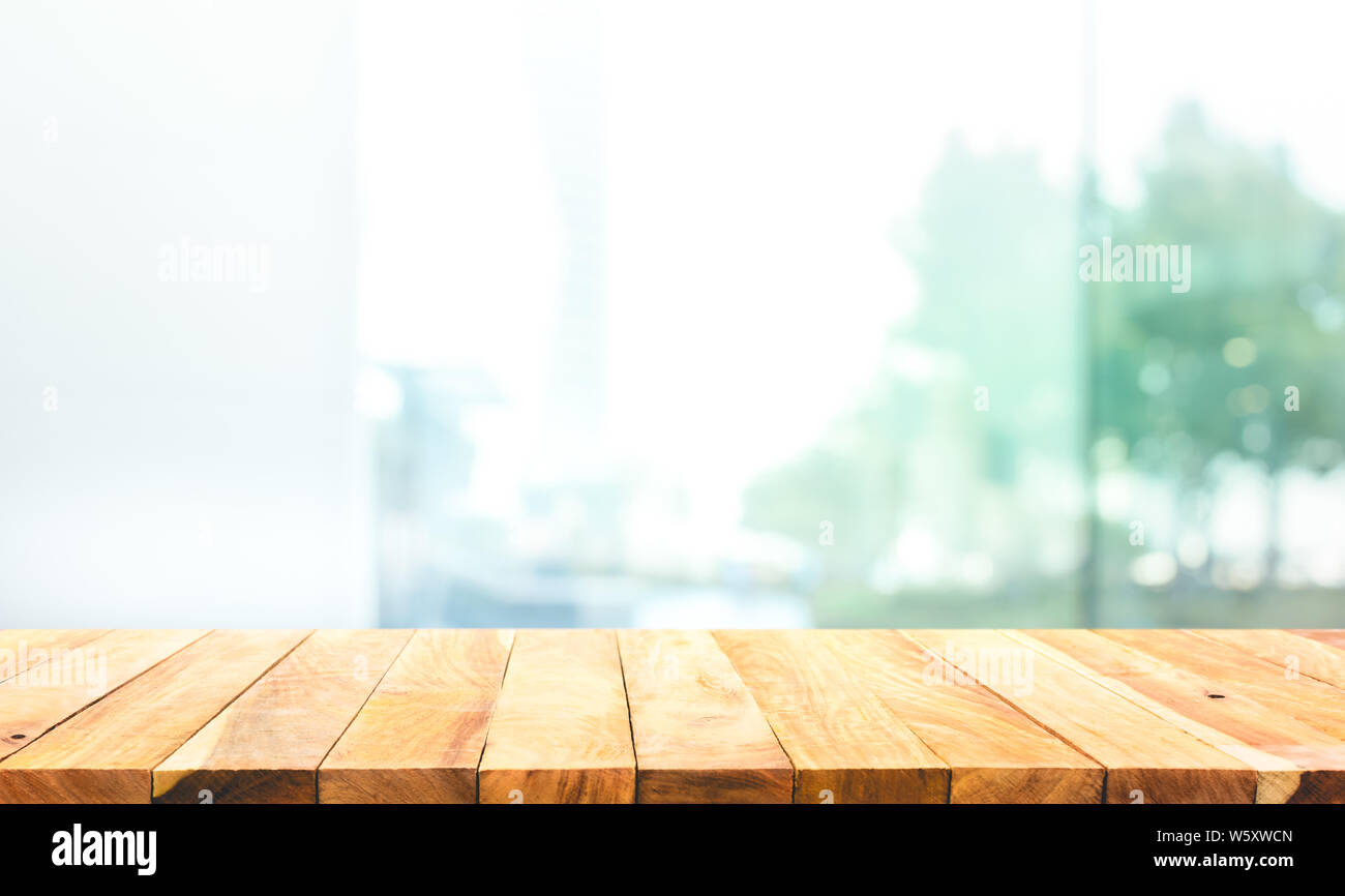 Wood table top on blur window glass,wall background with city view.For ...