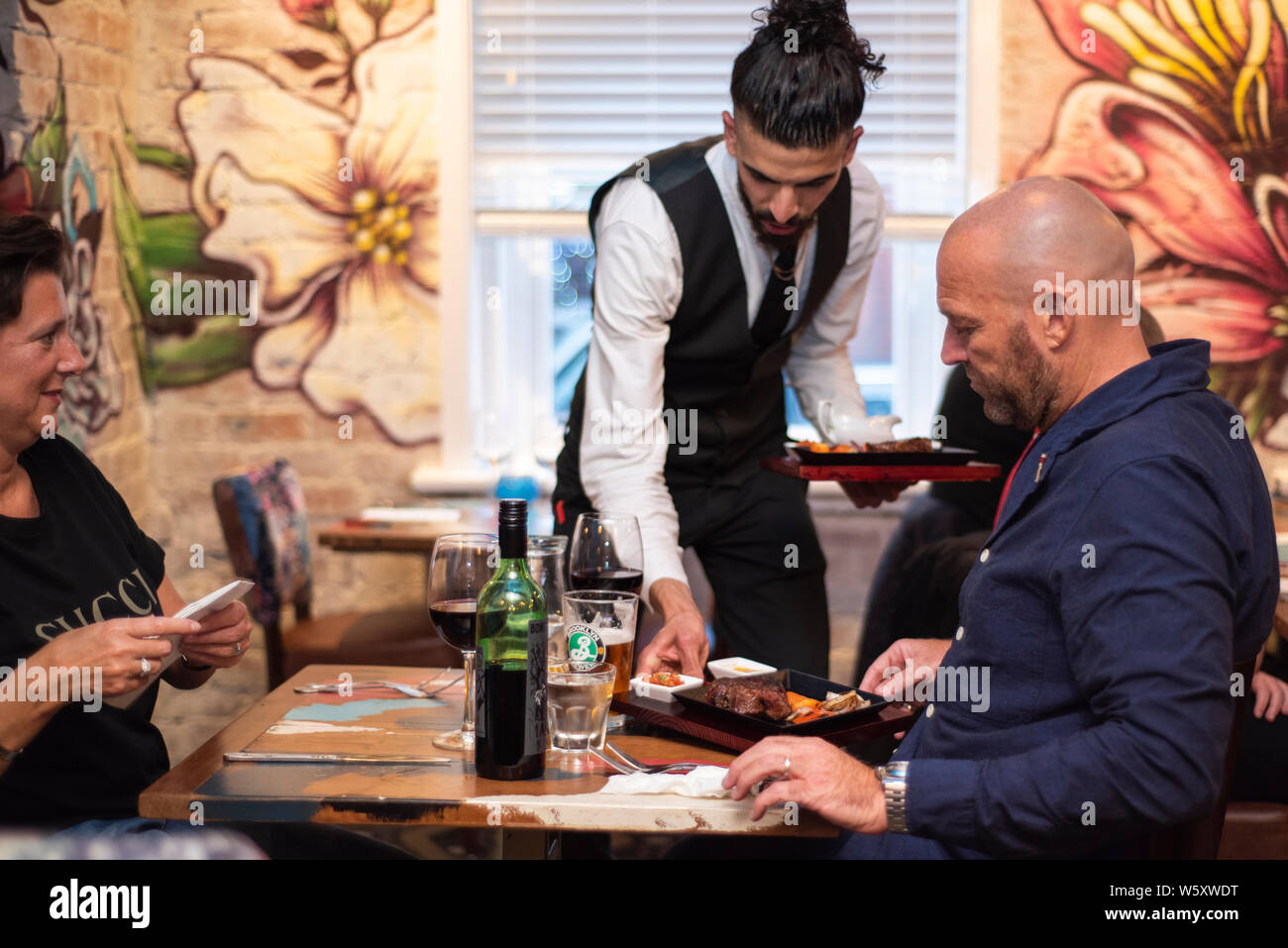 Doncaster, UK - May 11 2019: A waiter serves a couple on a night out ...