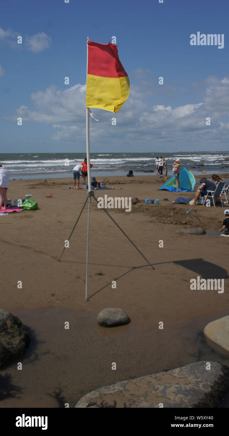 RNLI red and yellow warning flag on the beach in wales Stock Photo - Alamy