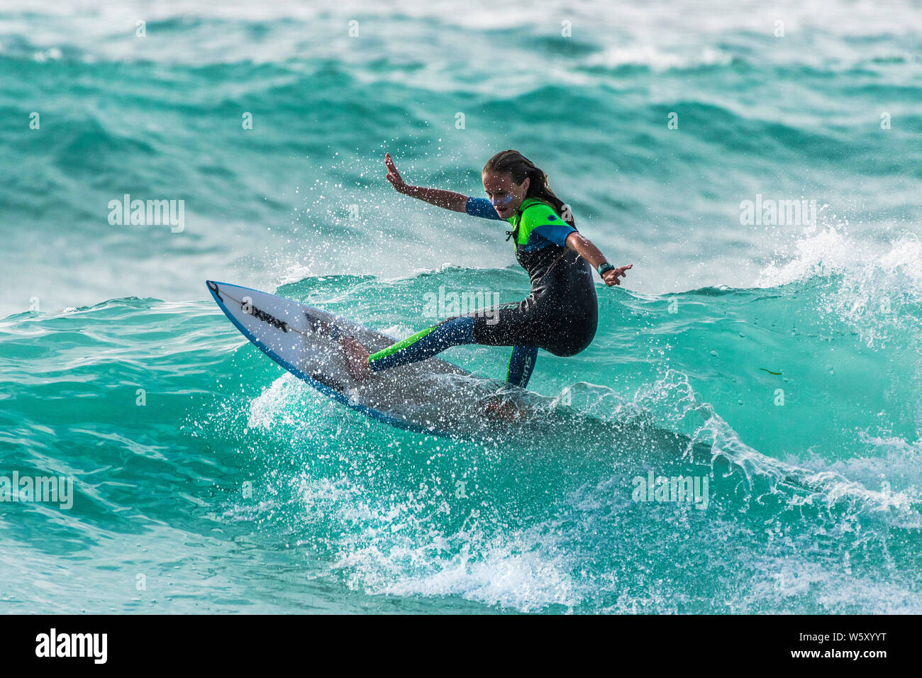 A young female surfer riding a wave at Fistral in Newquay in Cornwall ...