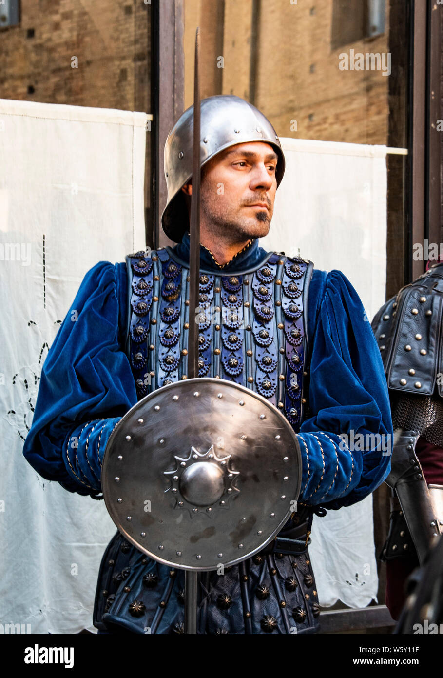 Man carrying sword and shield dressed in medieval costume for the Palio ...