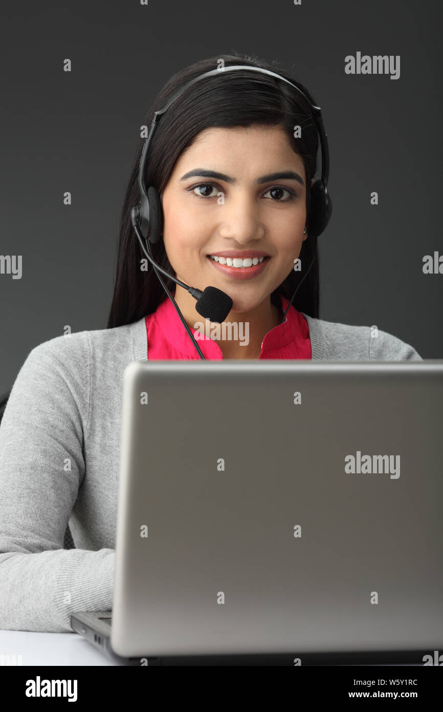Indian woman working on a laptop and wearing a headset Stock Photo - Alamy