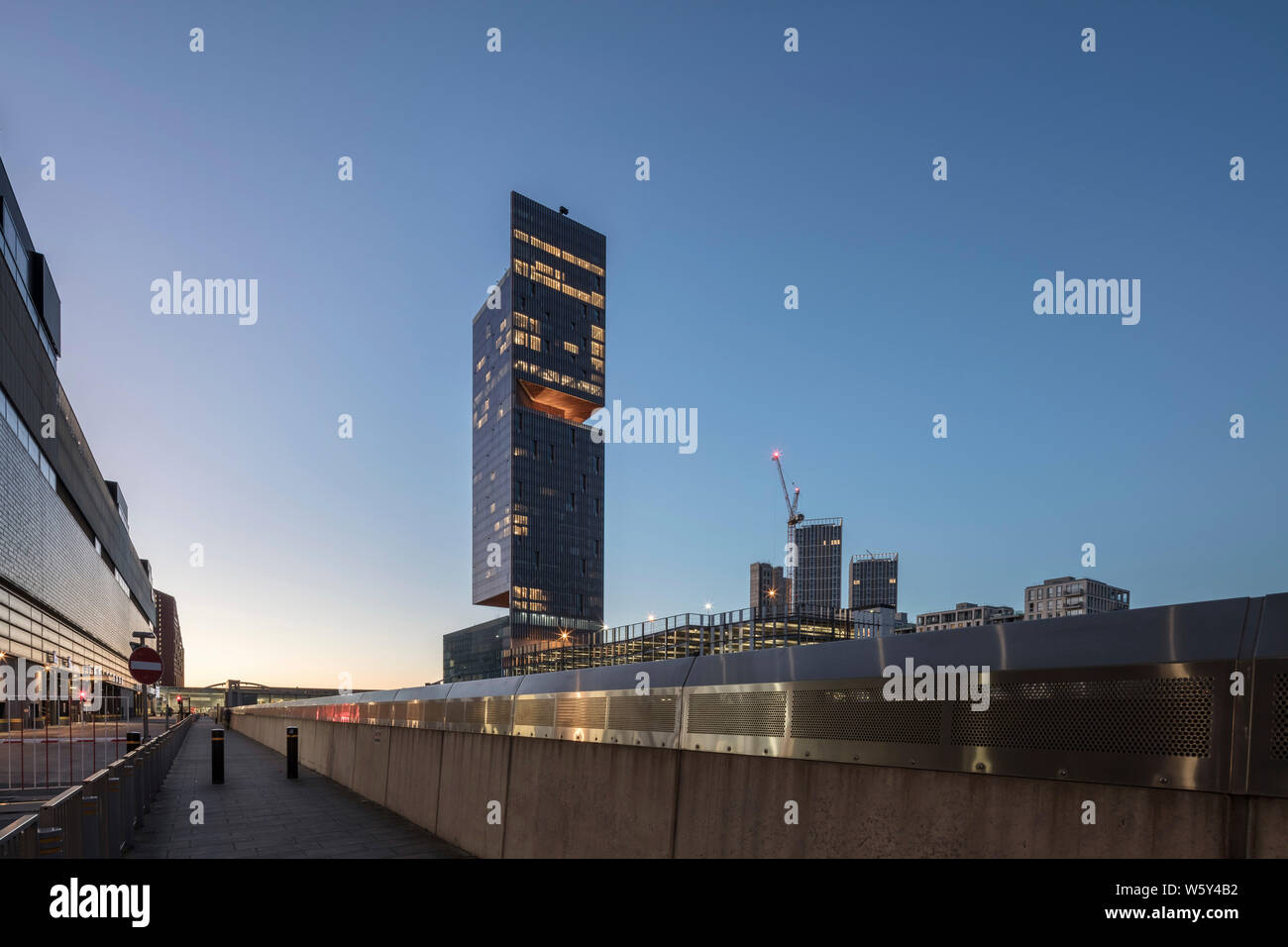 Elevation at dusk with lit interiors from Westfield loading docks. The ...