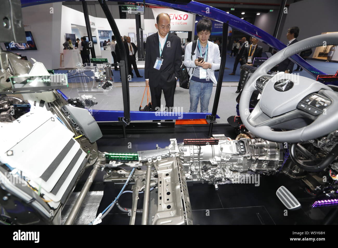 Visitors view the structure of a car on display at the stand of AISIN ...