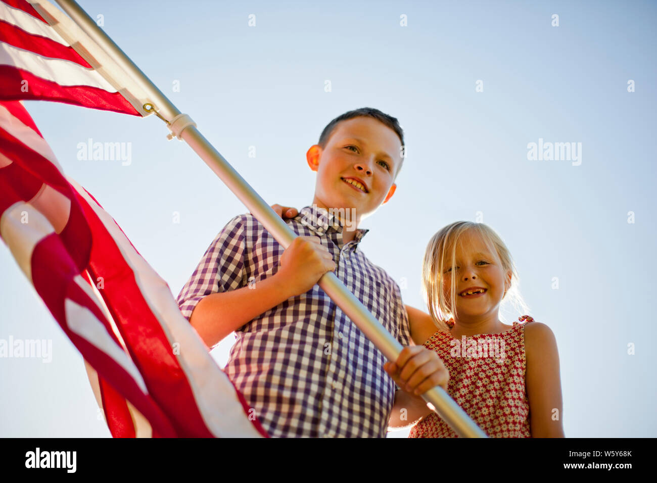 Portrait of a young boy and his sister holding an American flag Stock ...