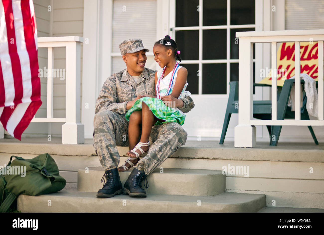 Happy young girl and her father sitting together on the front porch of ...