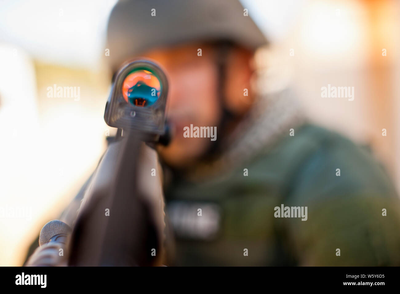 Mid adult army soldier aiming a gun while wearing a protective helmet ...