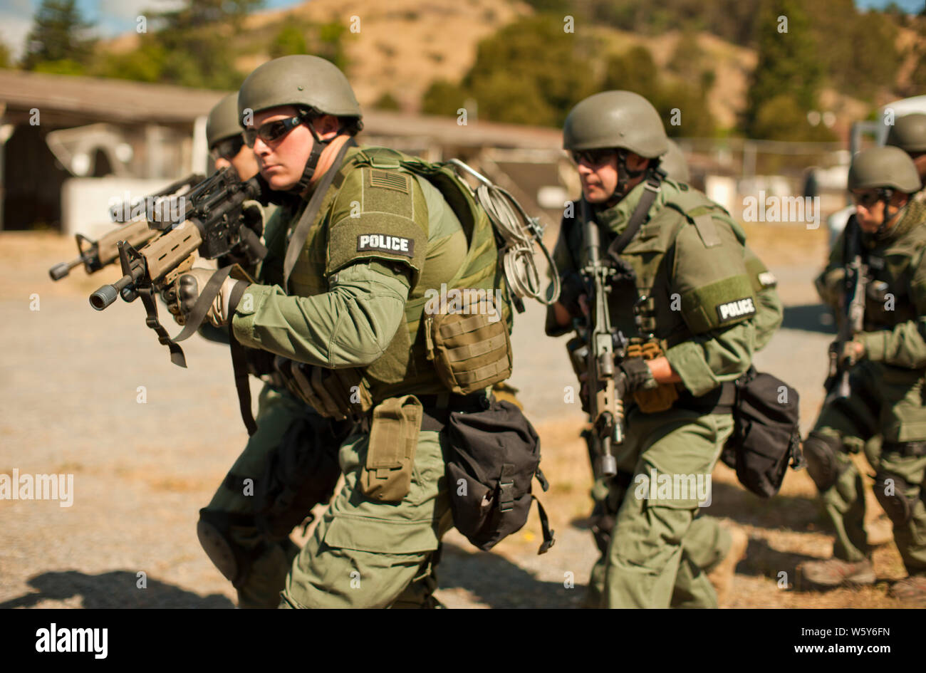 Team of armed military police holding guns while running through a ...