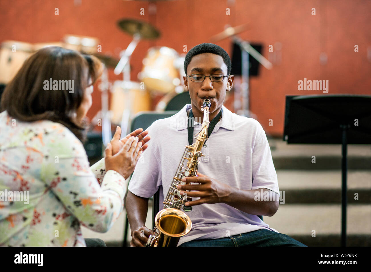 Young man being instructed by music teacher Stock Photo - Alamy