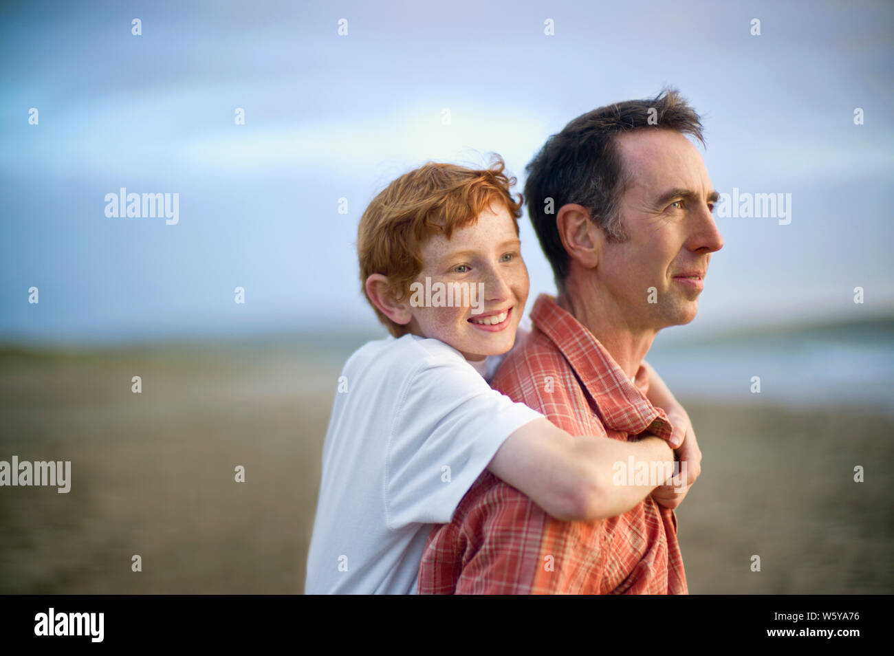 Mid adult man giving his smiling son a piggyback ride on a beach Stock ...
