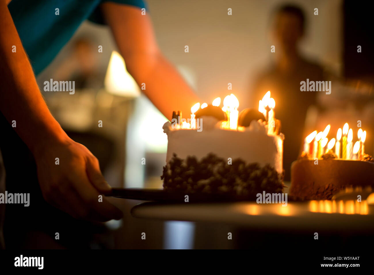 Arms of a mid adult man placing a glowing birthday cake on a table ...