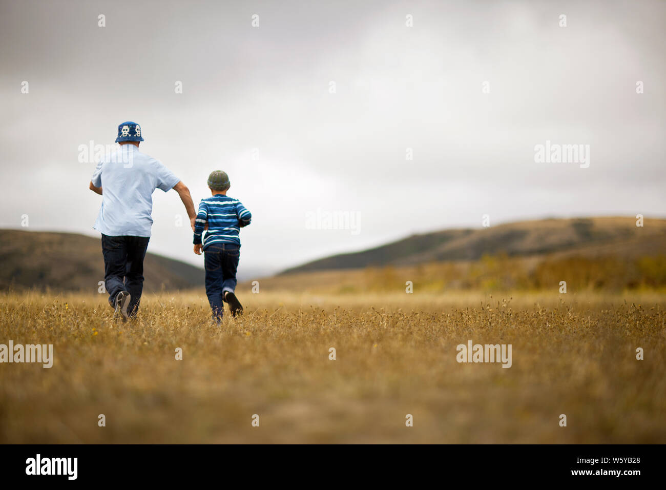 Young boy and father running through a grassy field Stock Photo - Alamy