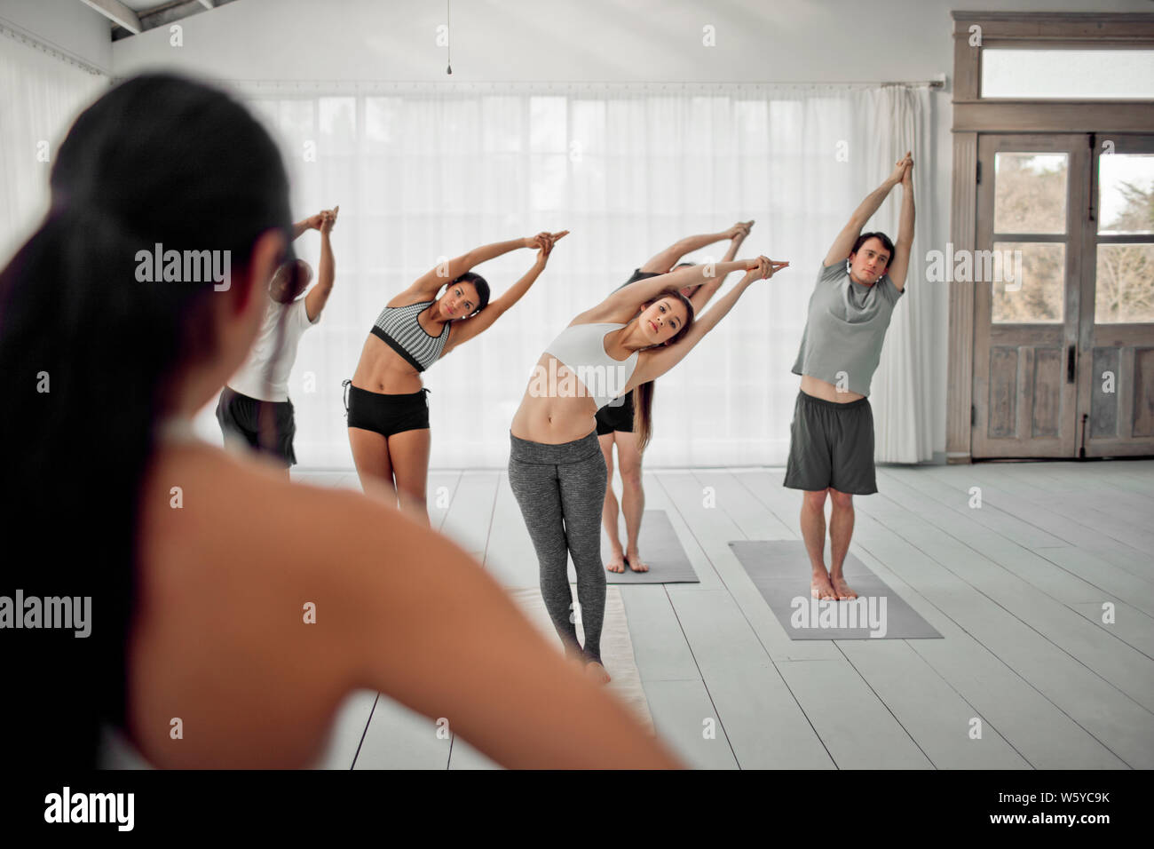 People stretching with their arms raised during a yoga class Stock ...