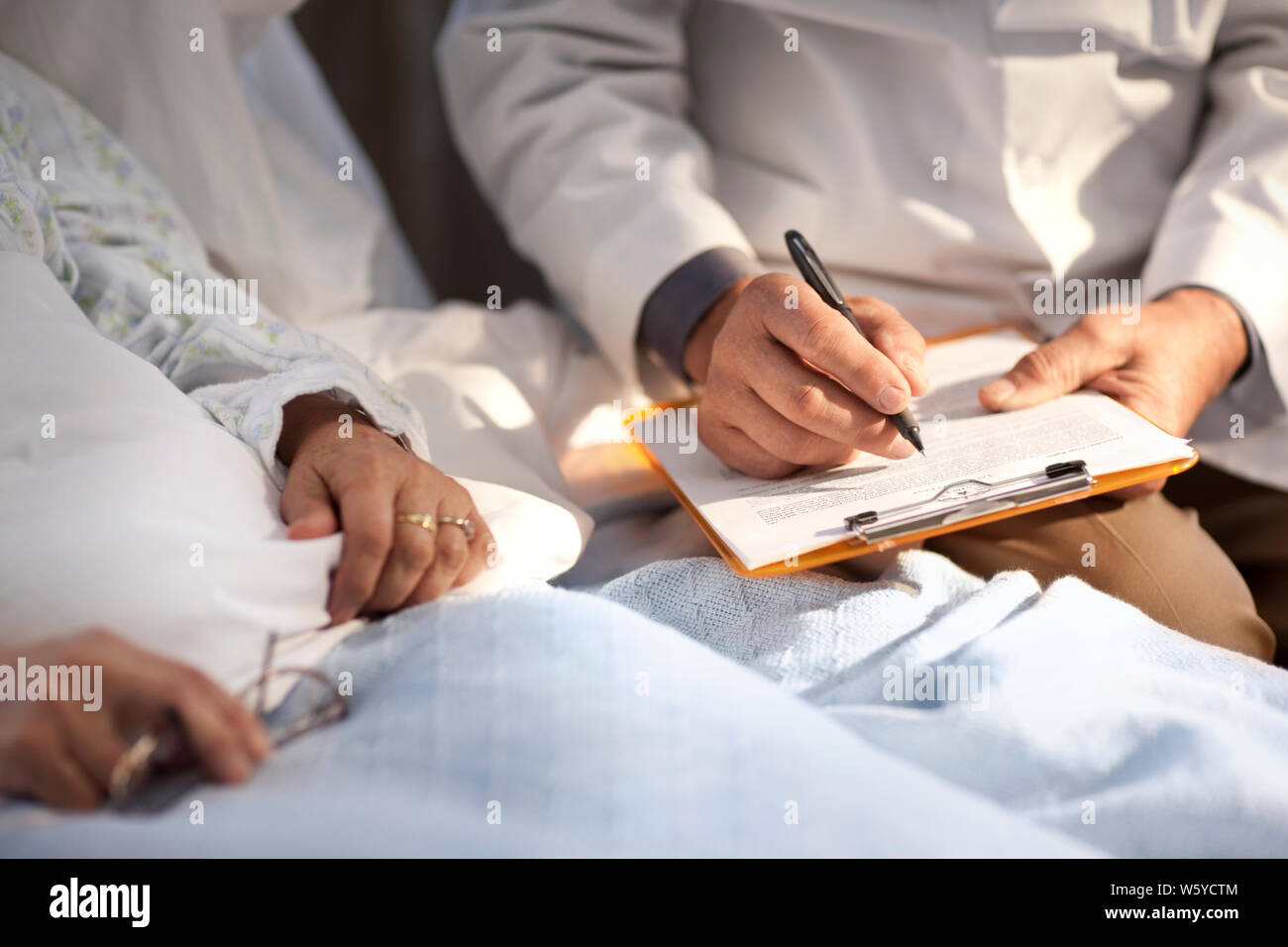 Doctor taking notes while sitting with a patient in hospital Stock ...