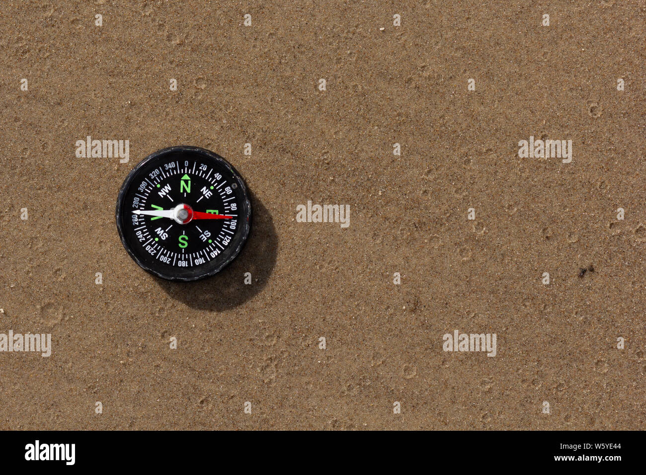 Compass pointing East laying on beach Stock Photo - Alamy