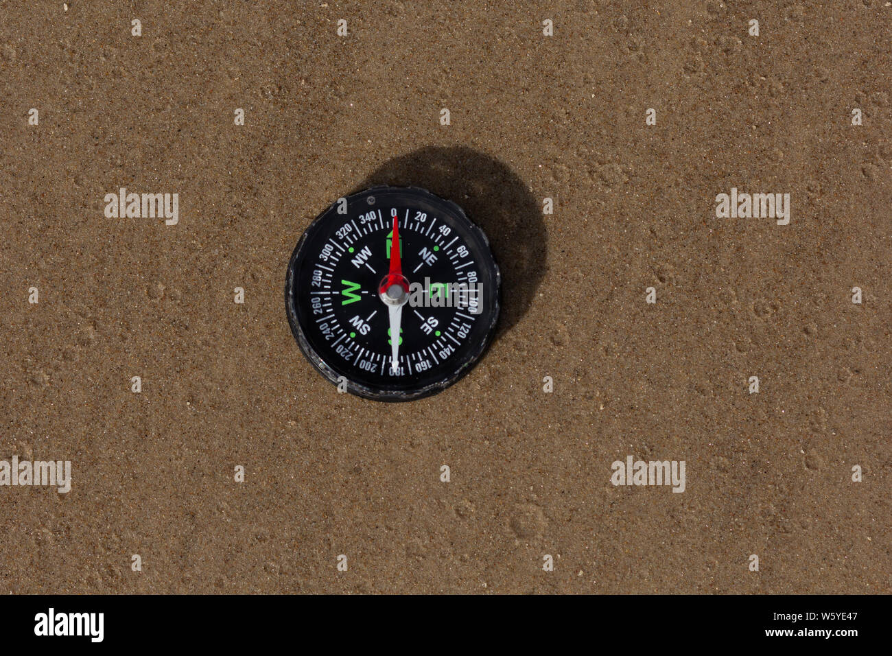 Compass pointing North laying on beach Stock Photo - Alamy