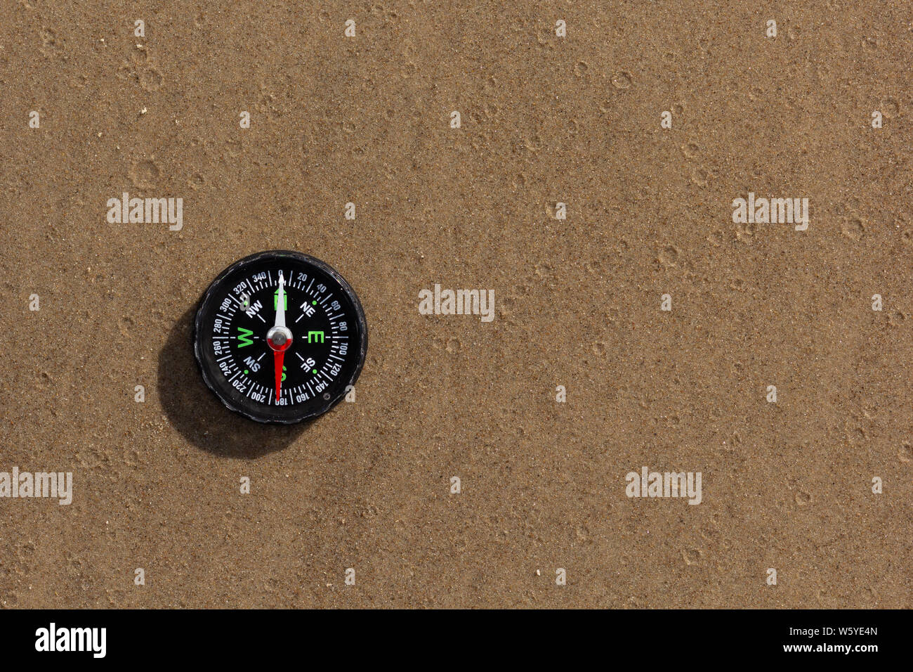 Compass pointing South laying on beach Stock Photo - Alamy