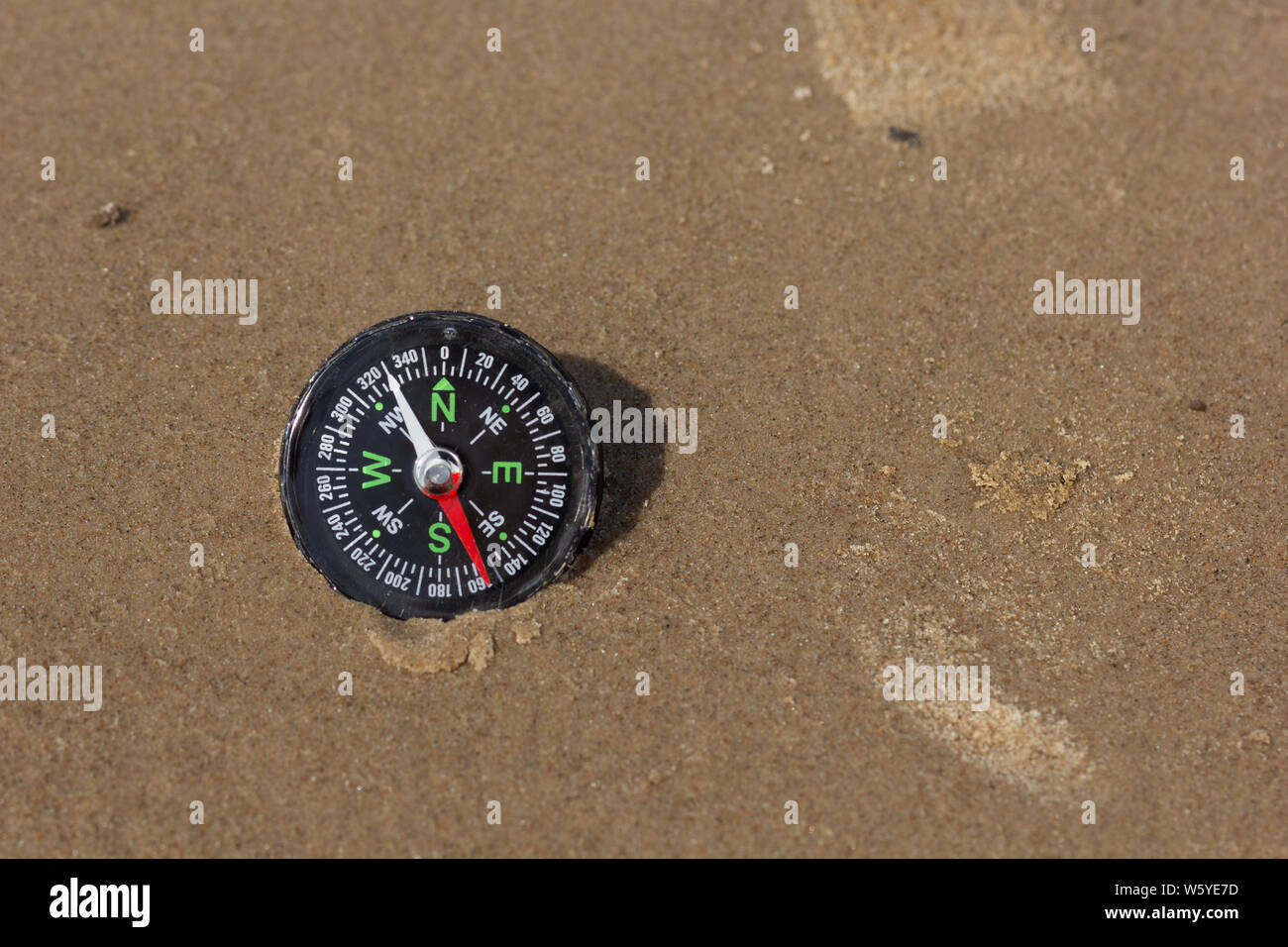 Compass pointing SouthWest laying on beach Stock Photo - Alamy