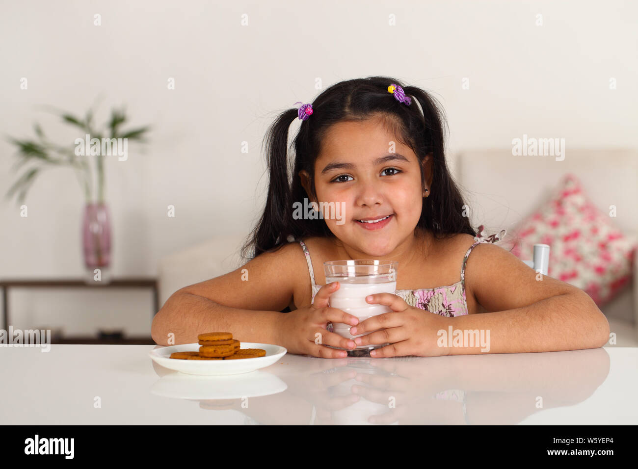 Girl smiling at breakfast table with a glass of milk Stock Photo - Alamy