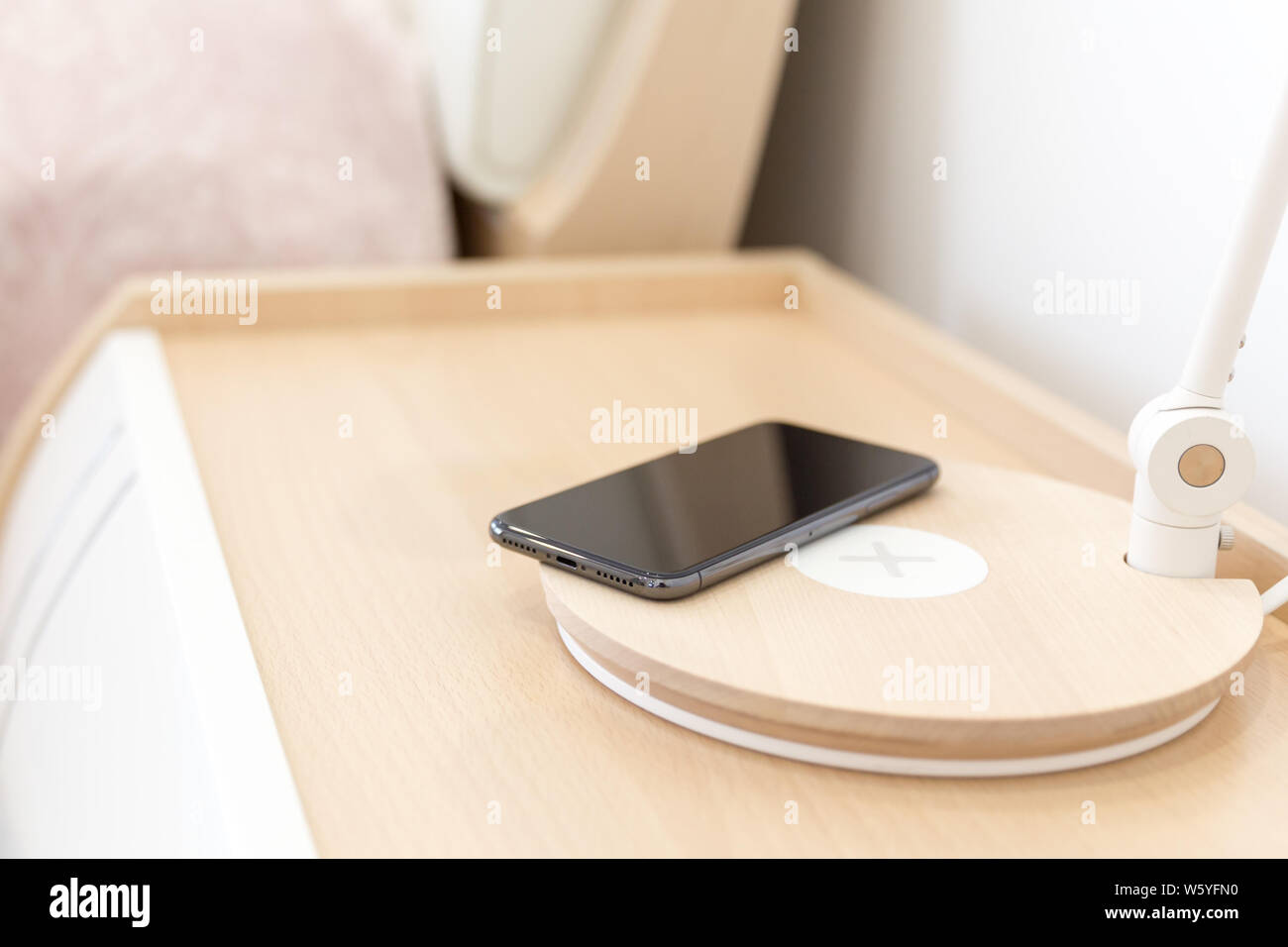 Wireless smartphone charging on lamp near bed Stock Photo - Alamy