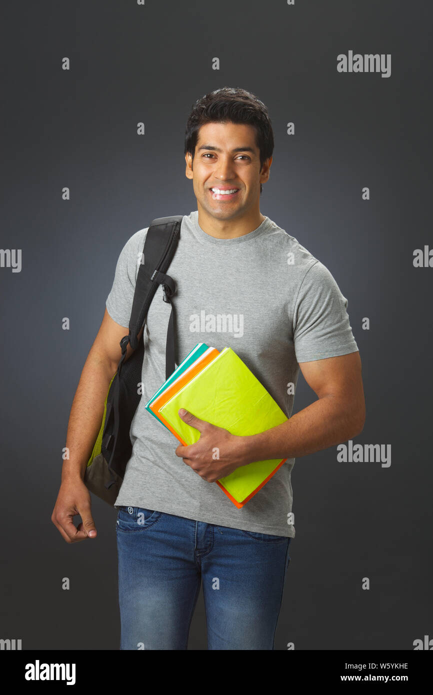 College student holding books smiling Stock Photo - Alamy