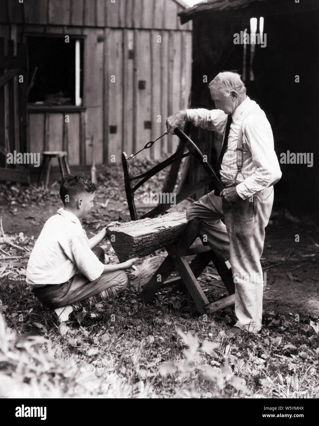 1930s BOY ASSISTING MAN BUCKING CUTTING FIREWOOD TO LENGTH BEFORE ...