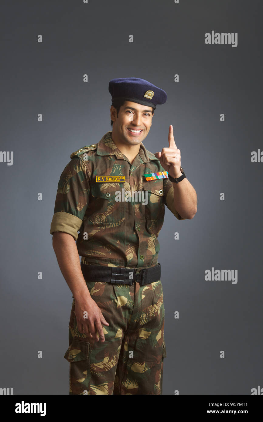 Army soldier pointing upward smiling Stock Photo - Alamy