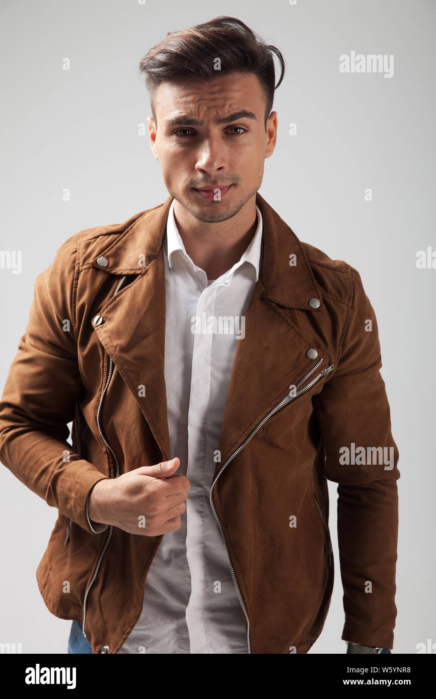 fashion man holding his collar on grey background Stock Photo - Alamy