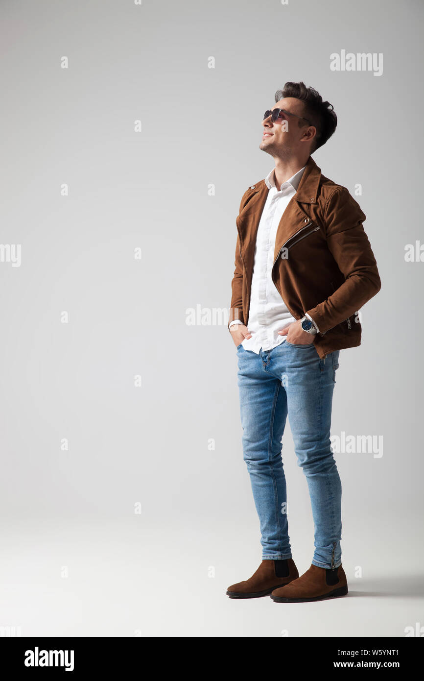 side view of a casual man looking up at something on grey background ...