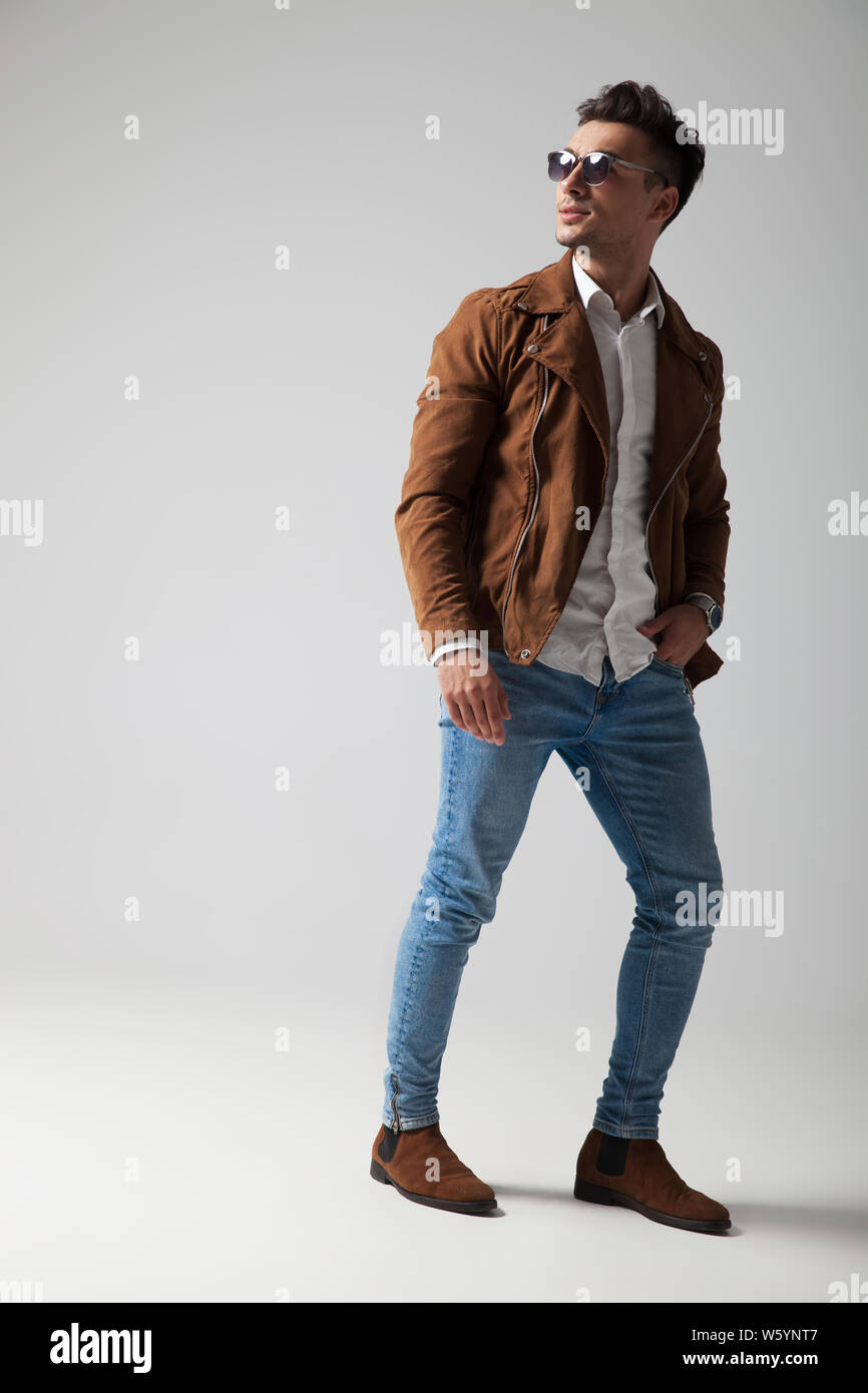 side view of a walking casual man looking back at something on grey ...