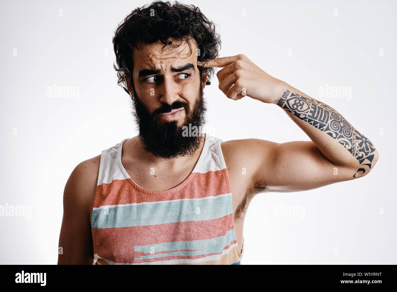 a young hipster making faces, with long hair and no shirt and tattoos ...