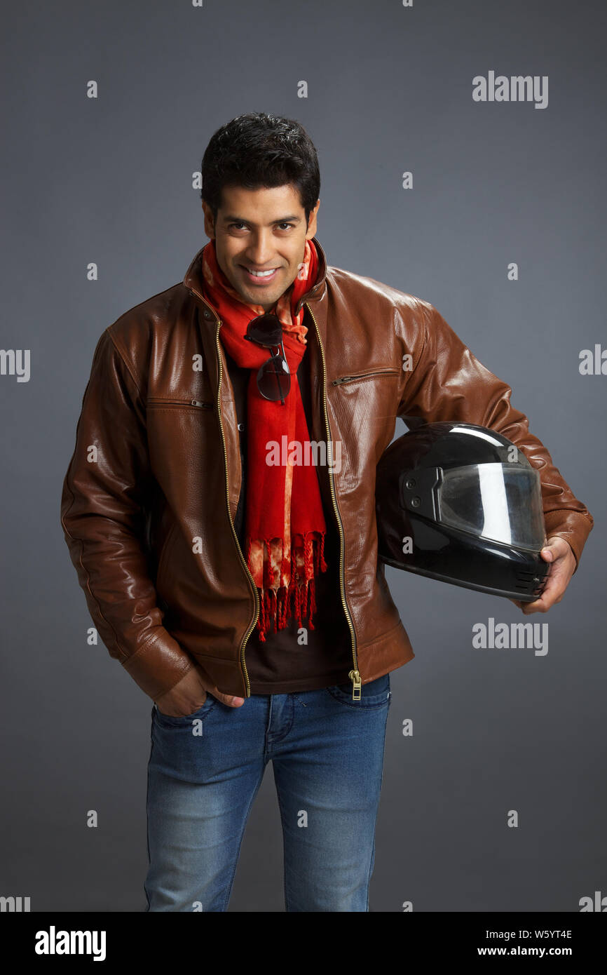 Biker holding helmet smiling Stock Photo - Alamy