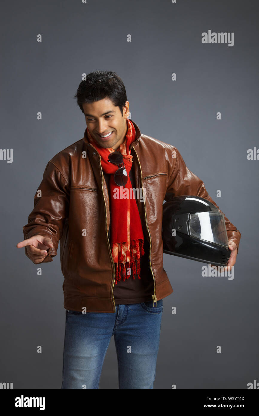 Biker holding helmet smiling Stock Photo - Alamy