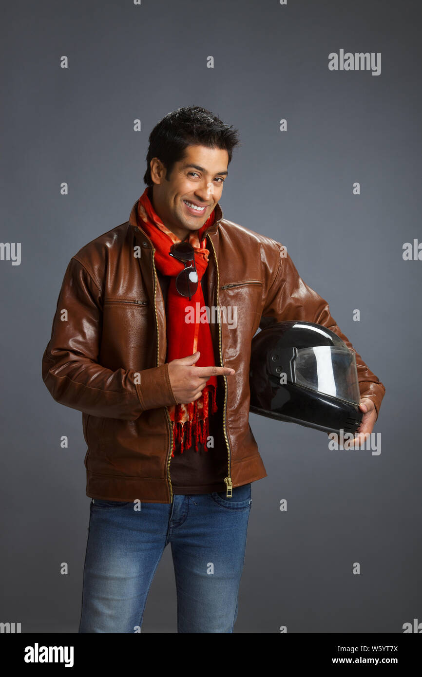 Biker holding helmet smiling Stock Photo - Alamy