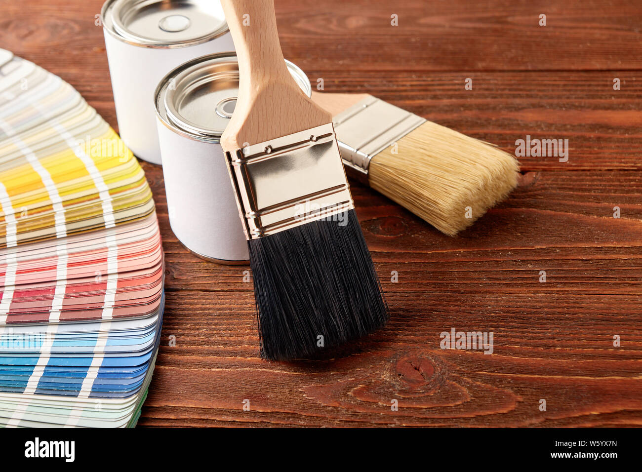 Two painting brushes, cans with paint, color guide palette on wooden ...